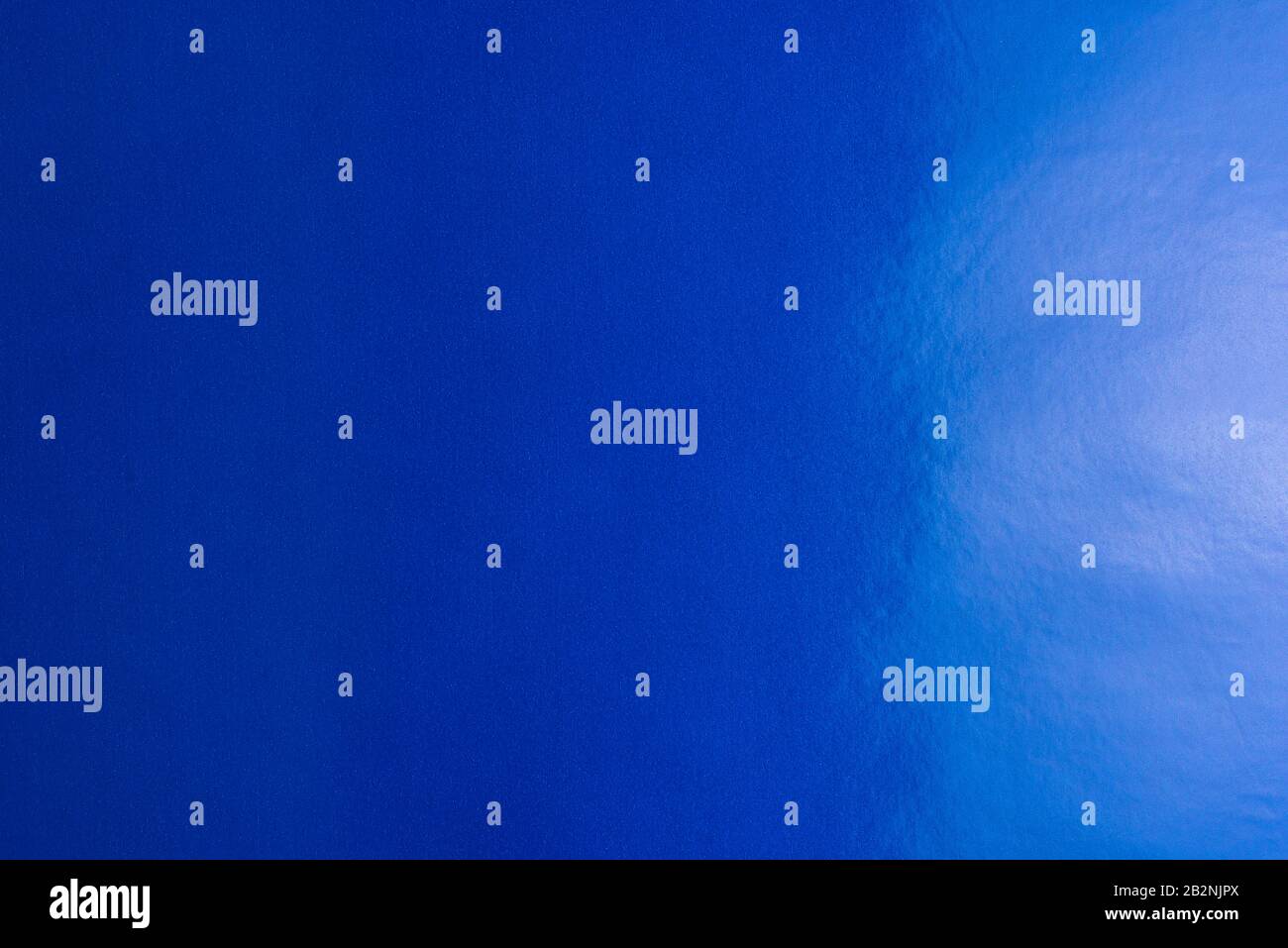 Blue background of real, shiny colored paper, illuminated by a soft ...