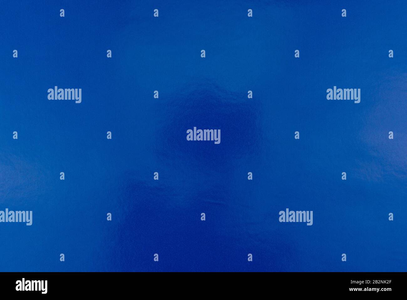 Blue background of real, shiny colored paper, illuminated by a soft ...