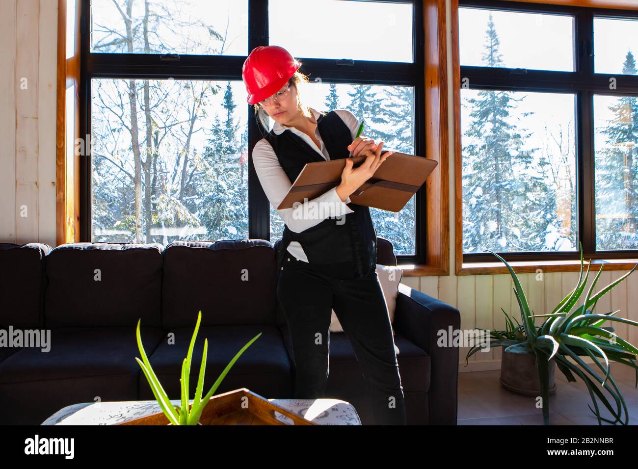 home inspector woman wearing red hard hat takes professional notes on ...