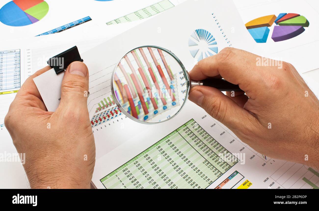 magnifying glass in hand and working paper chart Stock Photo - Alamy