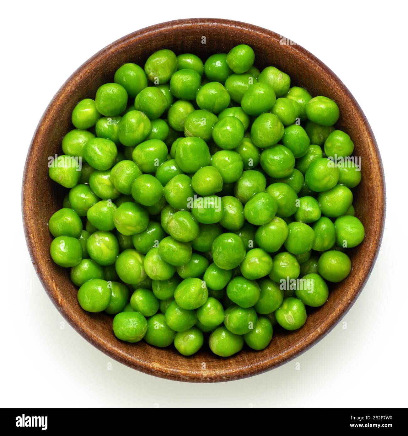 Fresh green garden peas in a dark wood bowl isolated on white. Top view ...