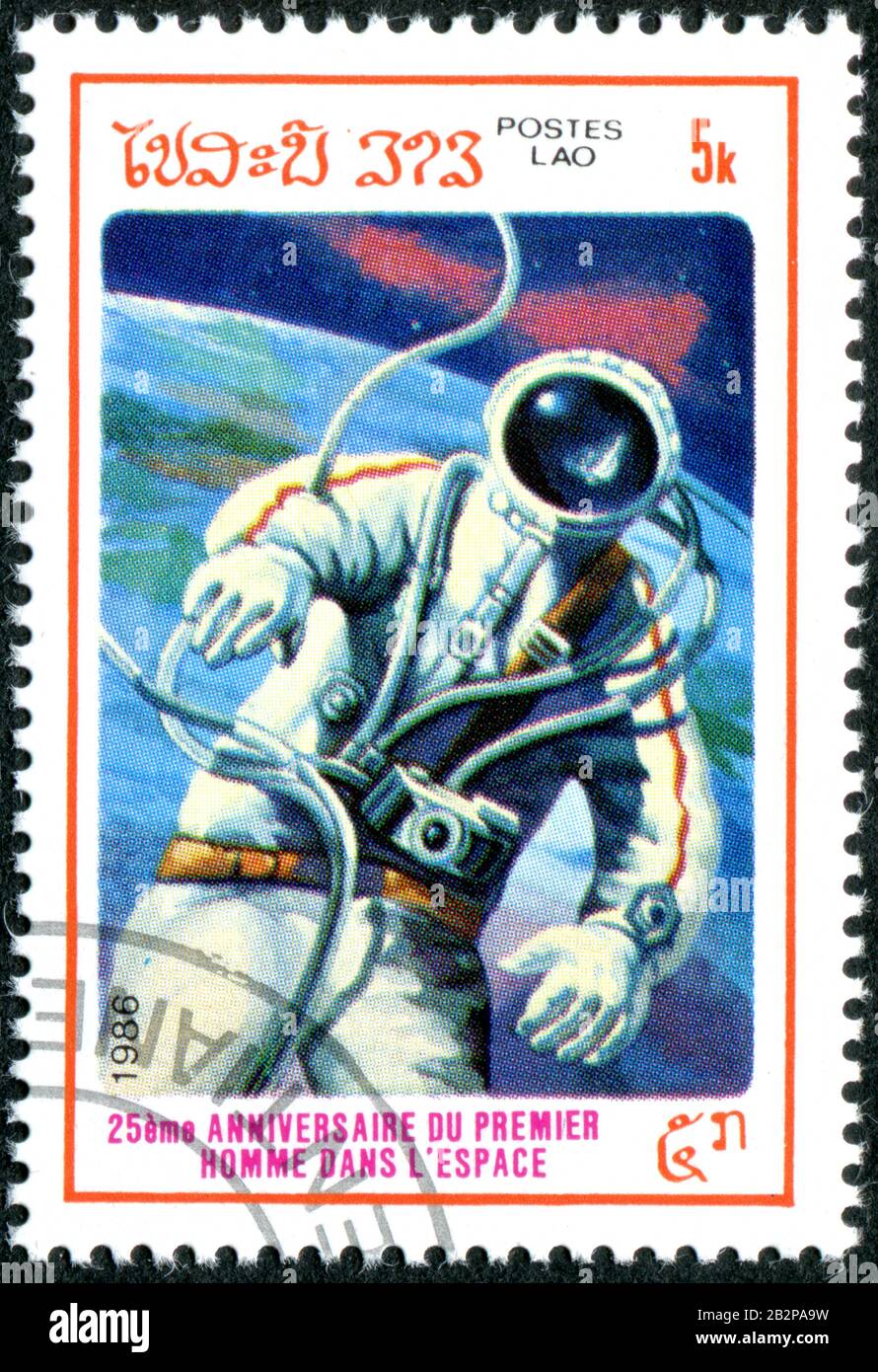 A stamp printed in Laos, dedicated to the 25th Anniversary of first man ...