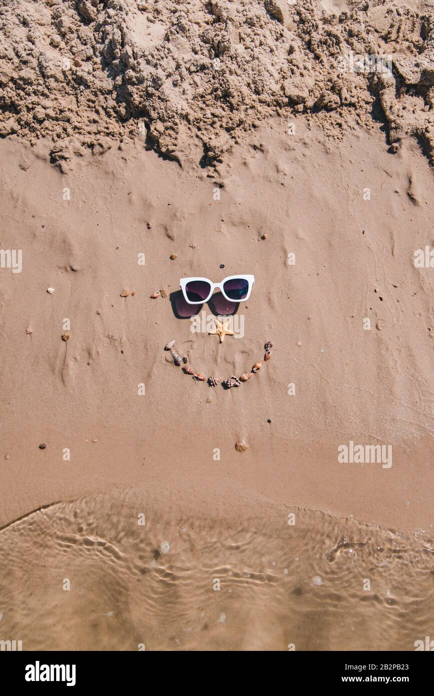 smile face drawn on sand with shells and sunglasses Stock Photo - Alamy