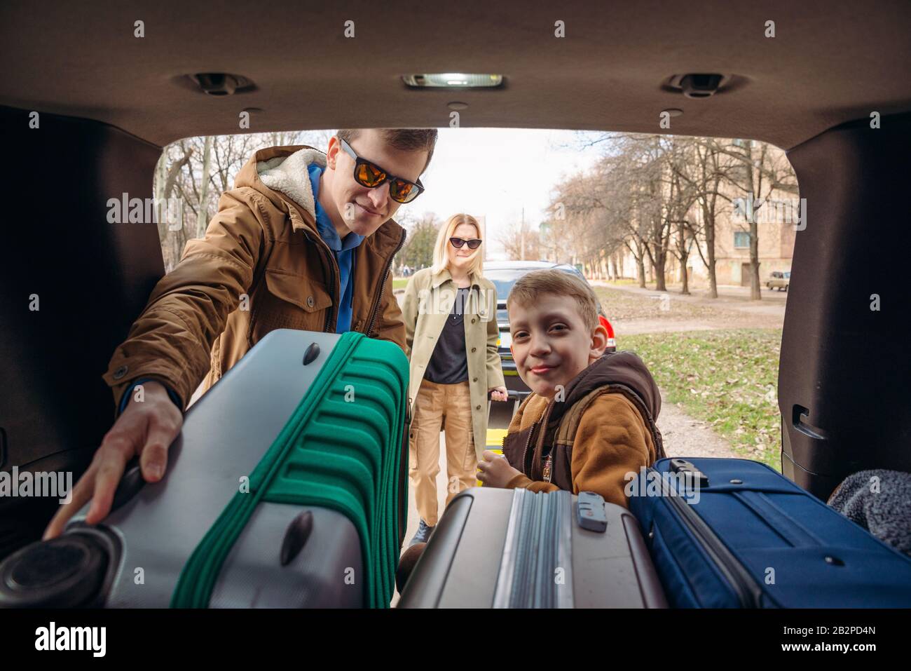 family with kid putting bag in car trunk Stock Photo - Alamy