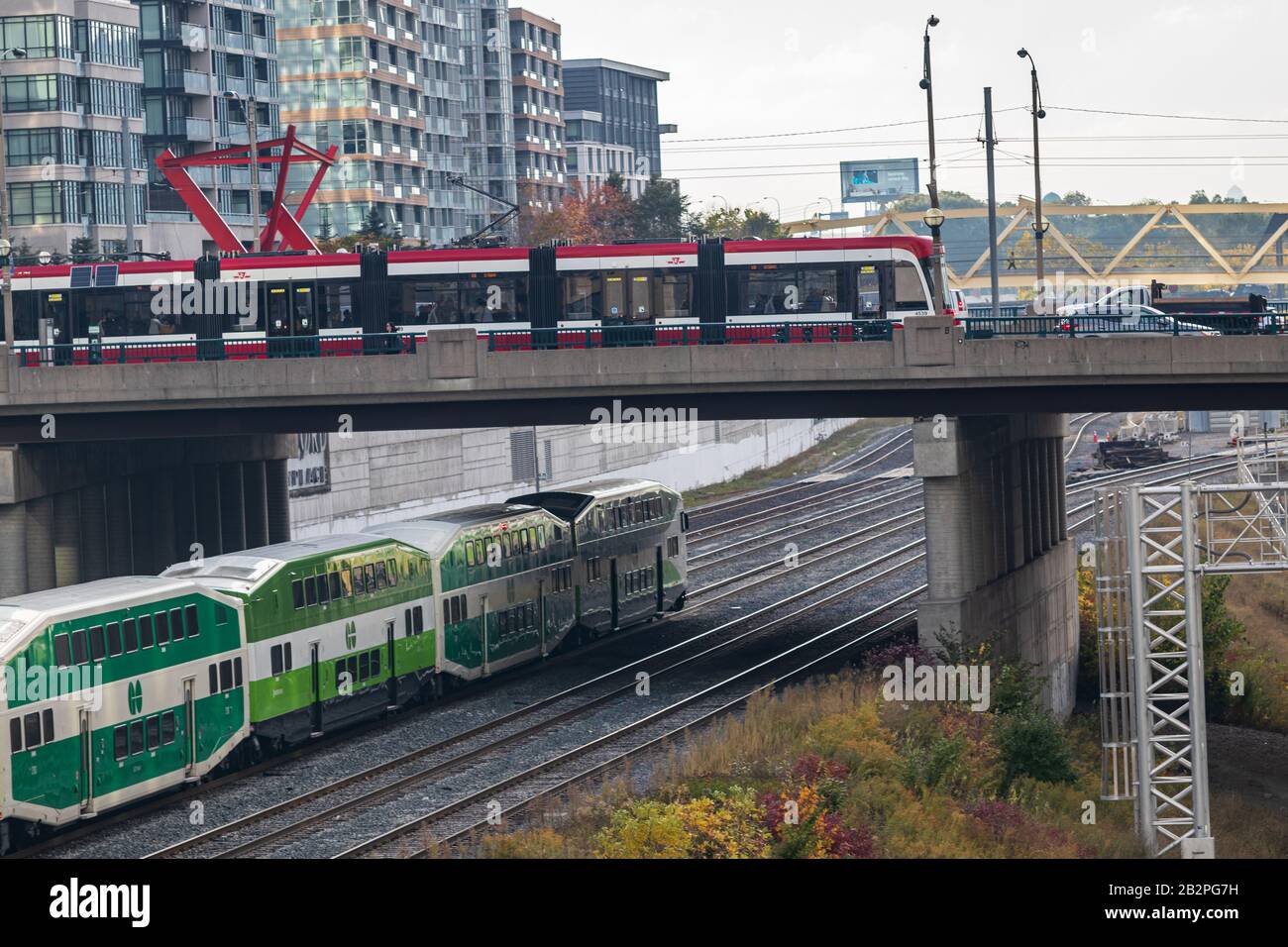 GO Transit Train seen passing under a bridge while a TTC streetcar goes ...