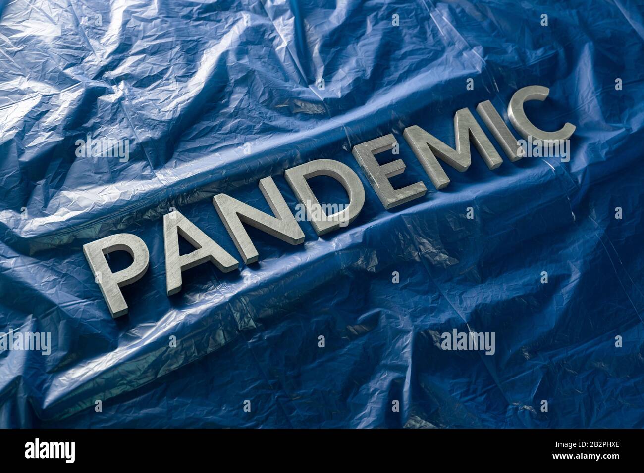 the word pandemic laid with silver letters on crumpled blue plastic ...
