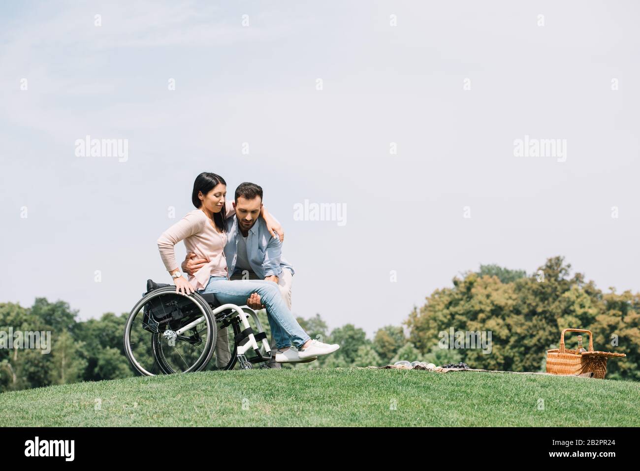 handsome young man taking young disabled girlfriend out of wheelchair ...