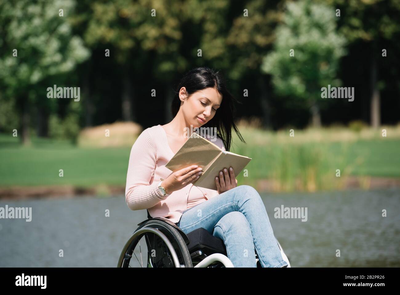 beautiful disabled woman smiling while reading book in park Stock Photo ...