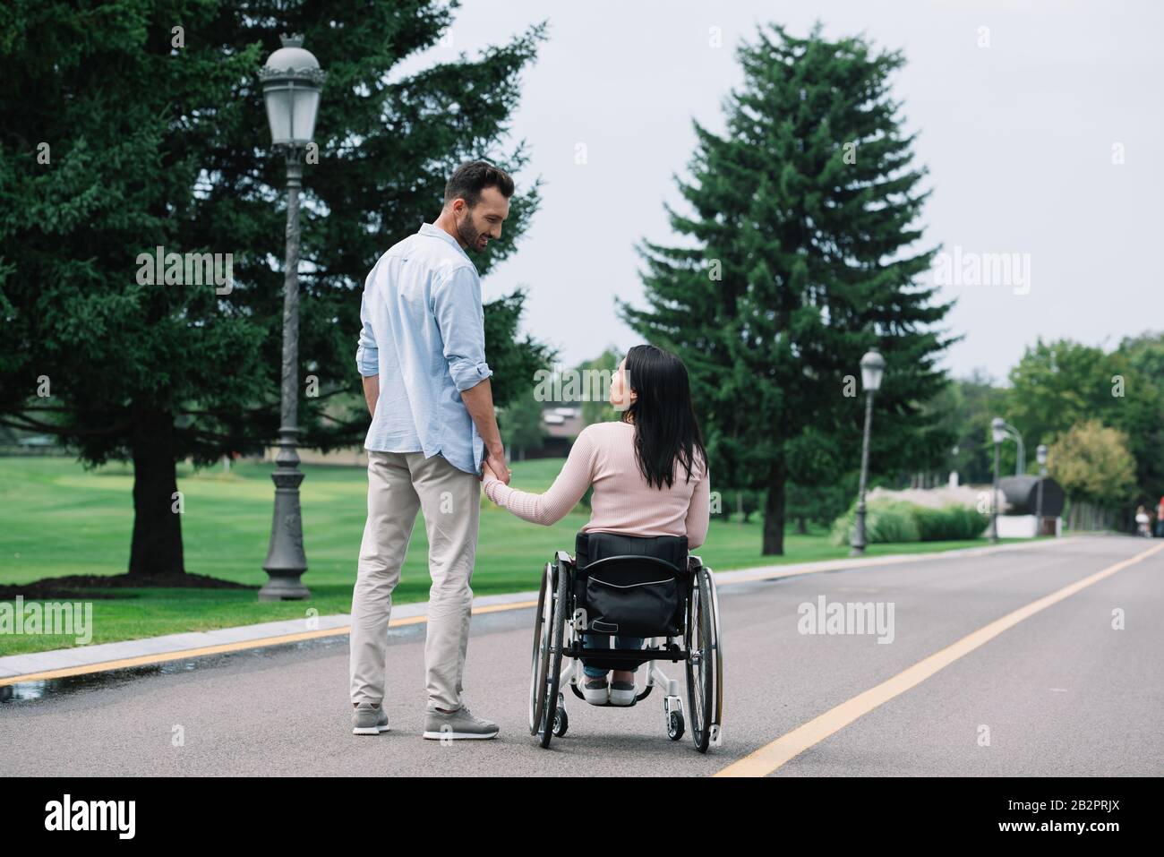 back view of young disabled woman holding hands with handsome boyfriend ...