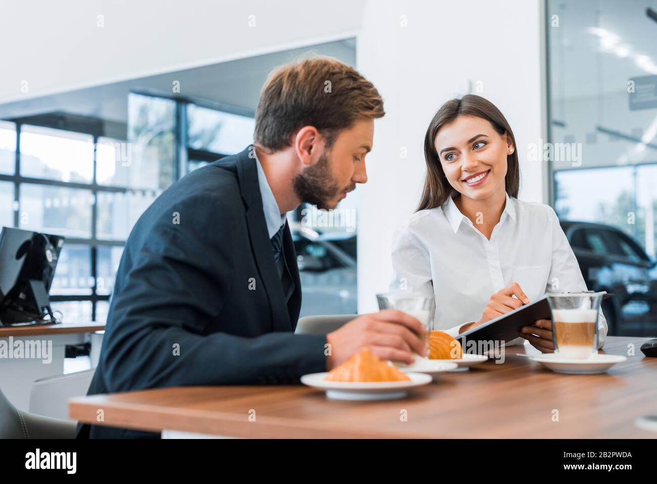 selective focus of attractive car dealer holding clipboard near man and ...