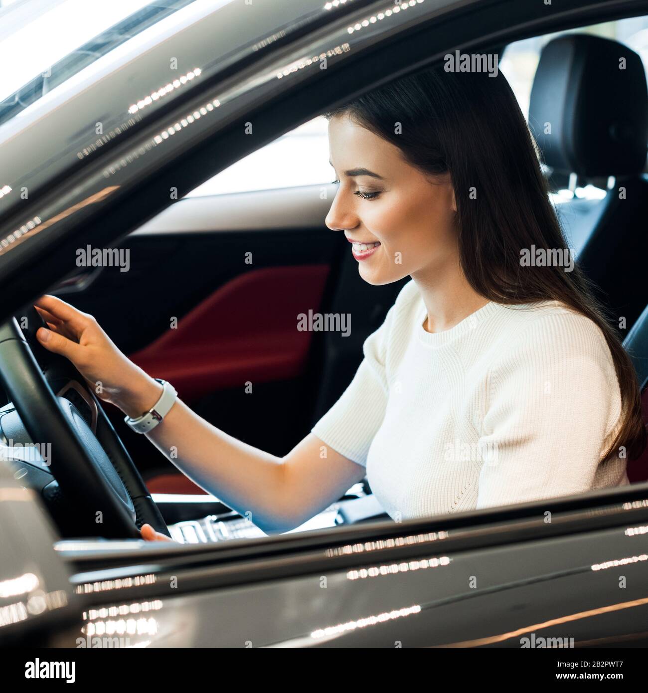 selective focus of happy woman touching steering wheel while sitting in ...