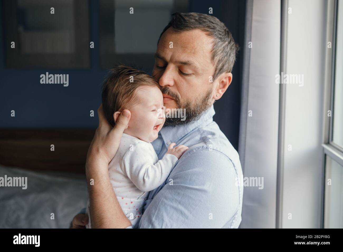 Middle age Caucasian father trying to calm down newborn baby. Man ...
