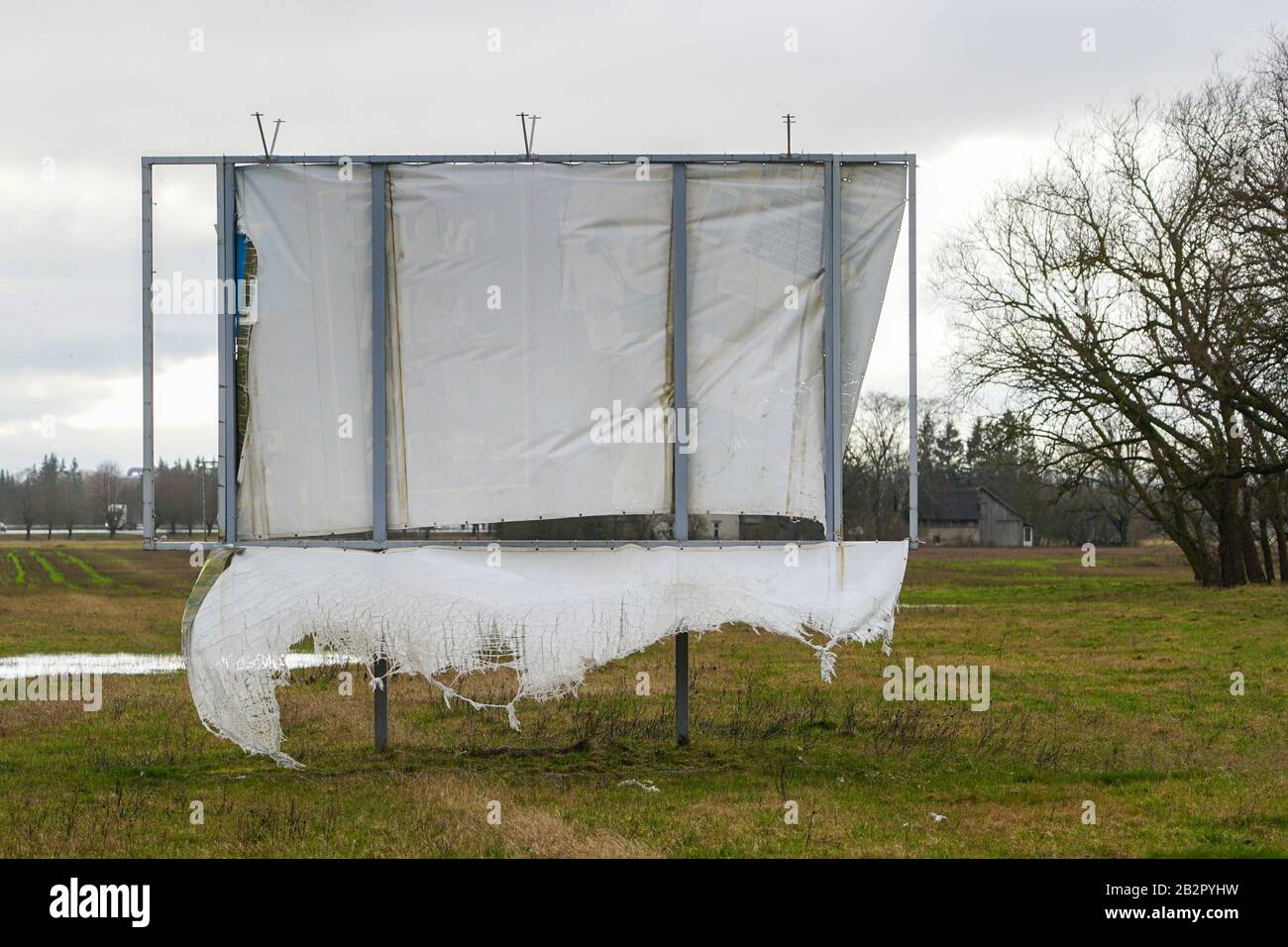 wind damaged advertising banner on the side of the road Stock Photo - Alamy