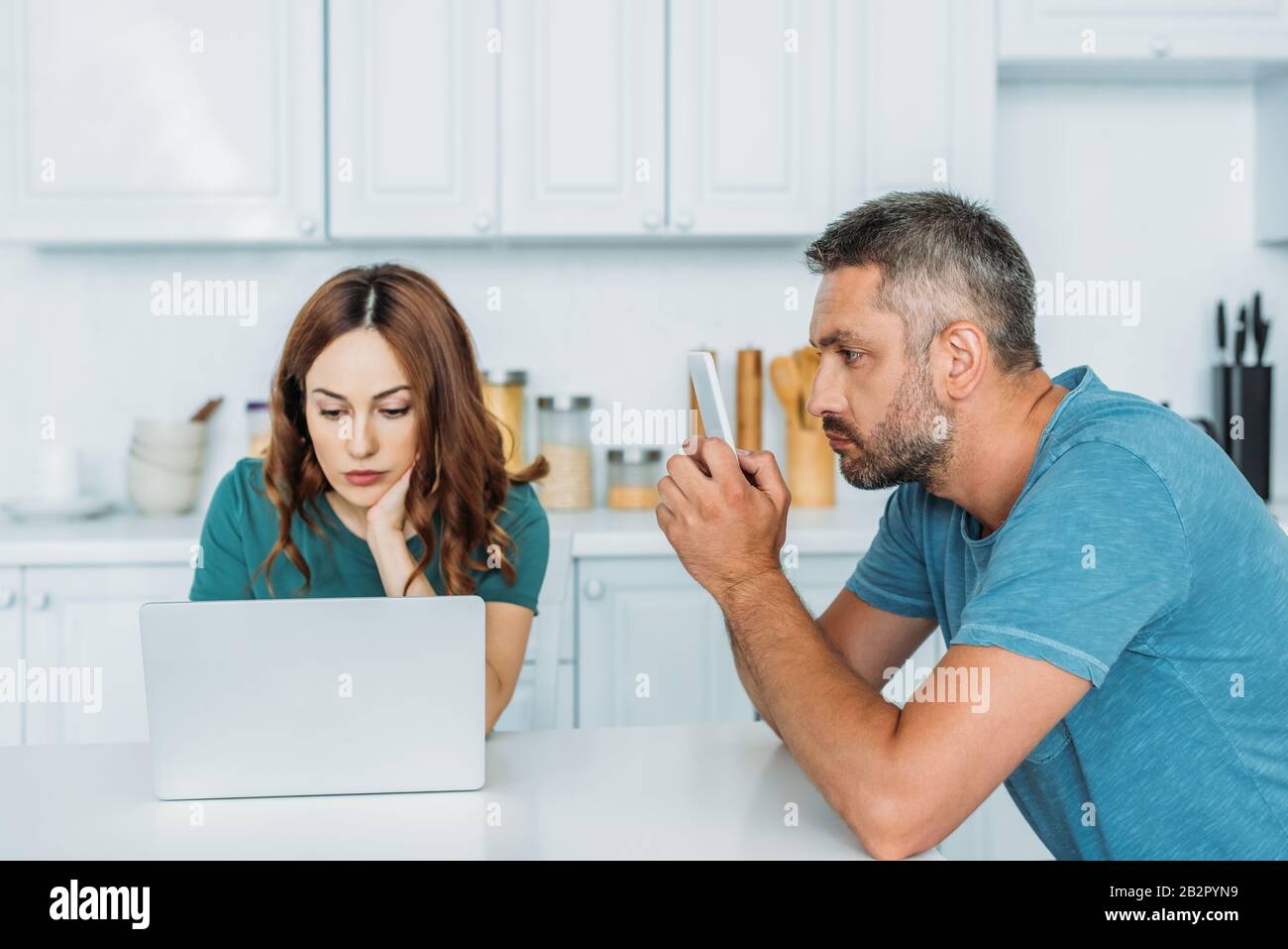 husband and wife sitting at kitchen table and using smartphones Stock Photo - Alamy