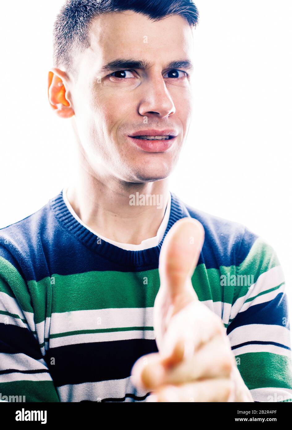 Portrait of a smart serious young man standing against white background ...