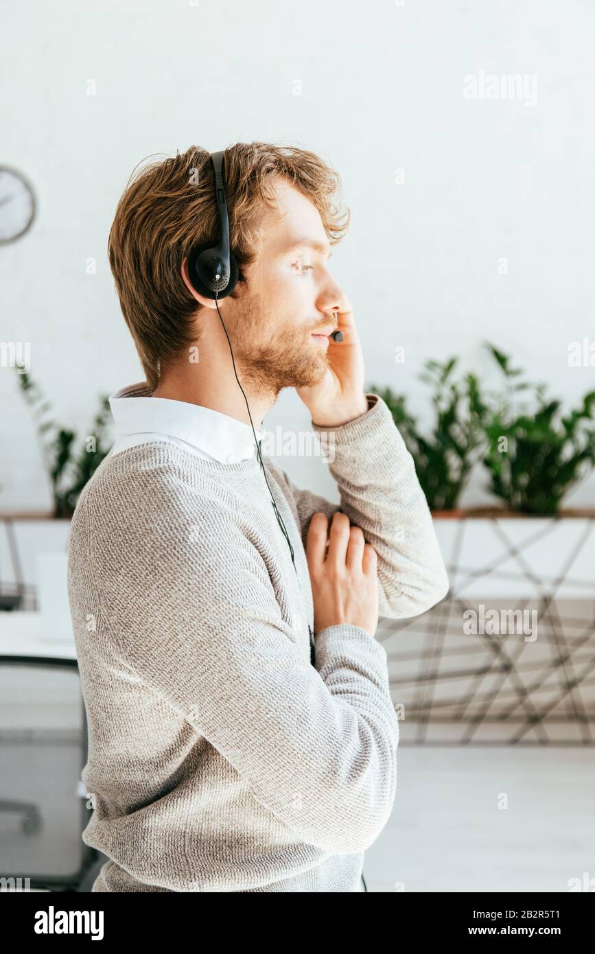 side view of handsome and bearded operator in brokers agency using ...
