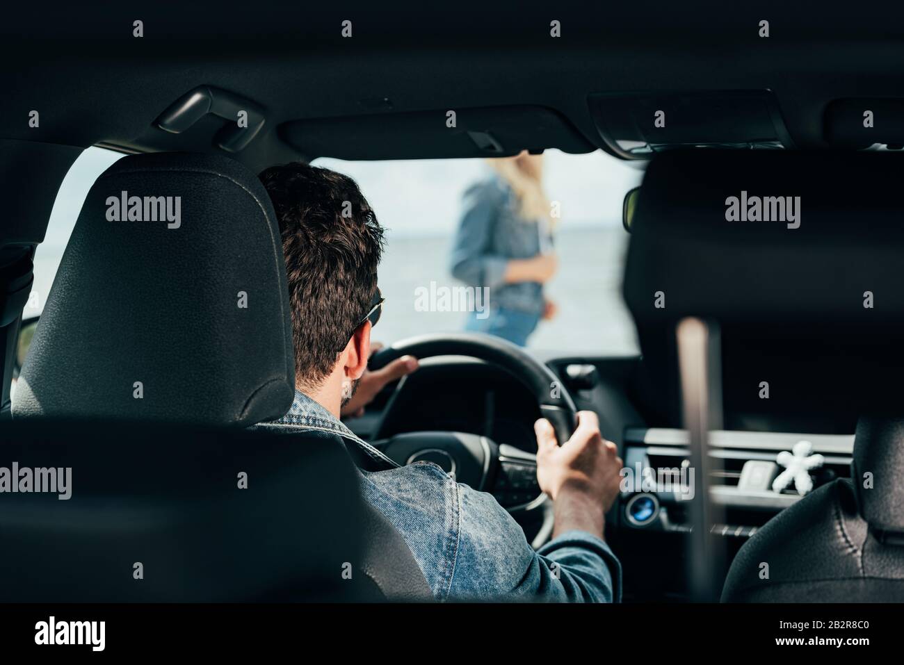 back view of man sitting in car and looking at woman Stock Photo - Alamy