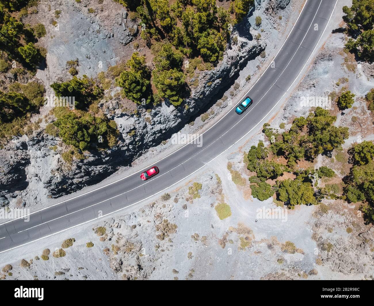Aerial view of two cars on the road surrounded by rocks and trees on a ...