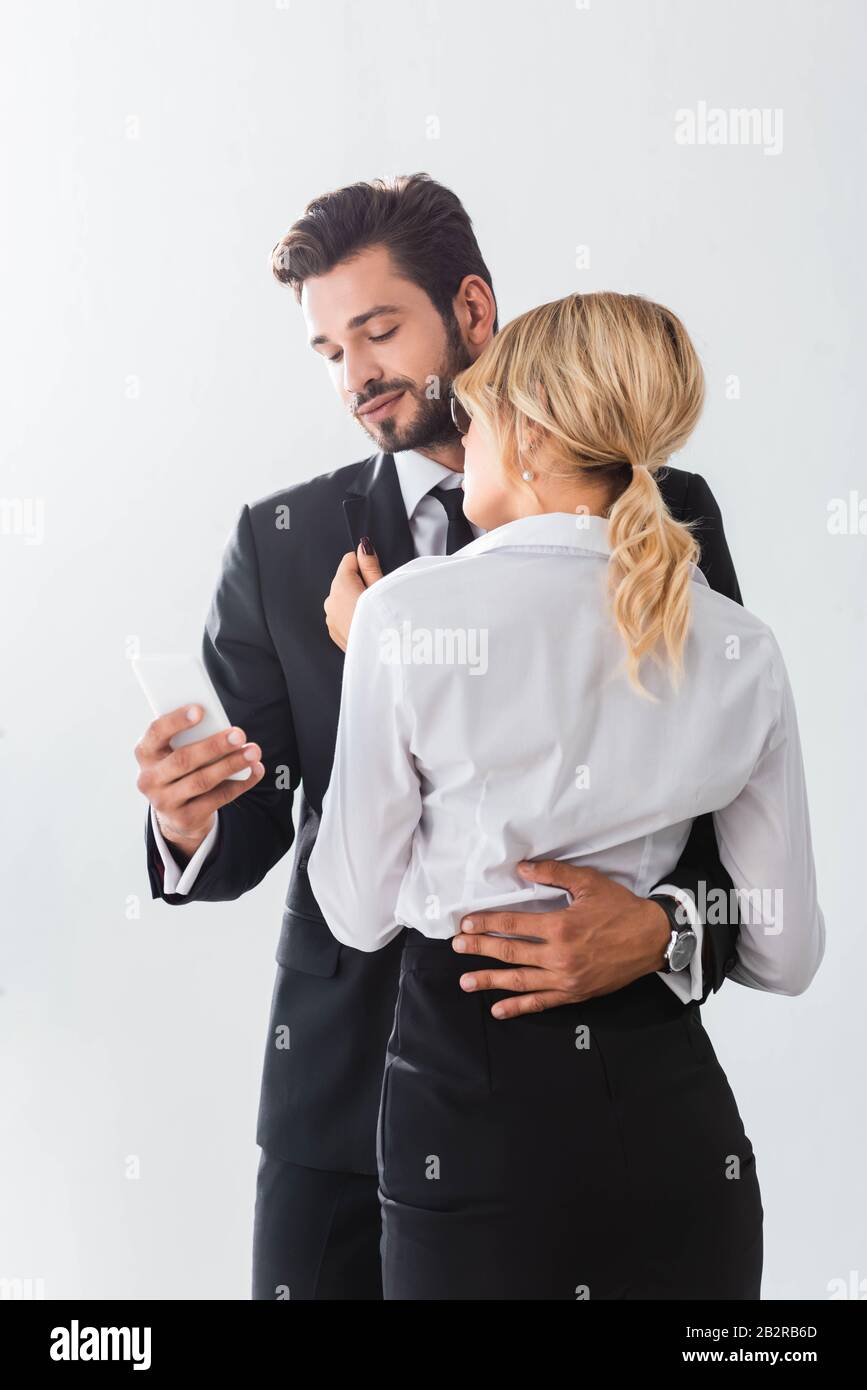 Businessman hugging woman and using smartphone Stock Photo - Alamy