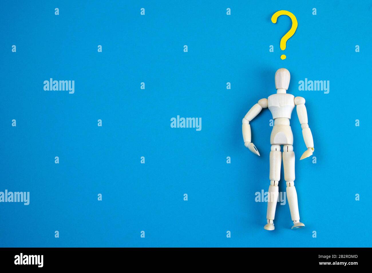 Wooden figurine of a man with question mark on a blue and pink ...