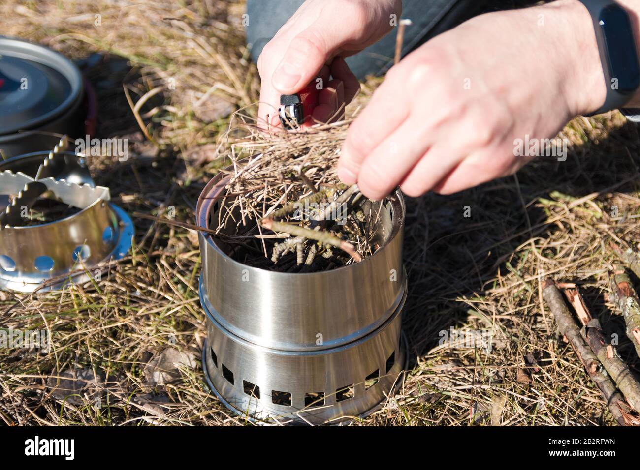 closeup man hands sets fire with straws and lighter in a portable wood ...