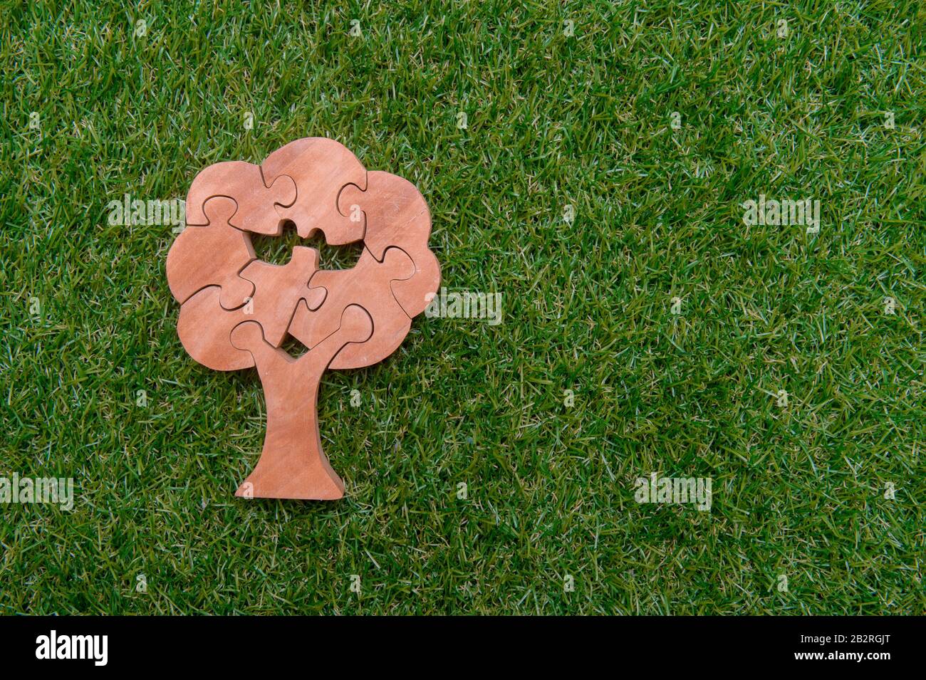 Wooden tree puzzle over green grass background Stock Photo - Alamy