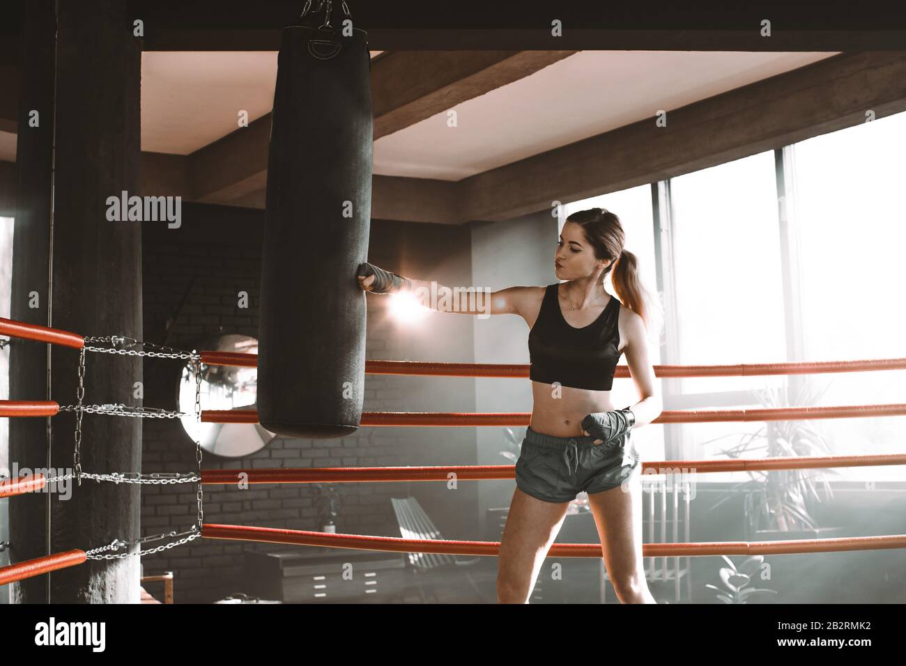 Female boxer hitting a huge punching bag at a boxing studio. Woman boxer training hard Stock ...