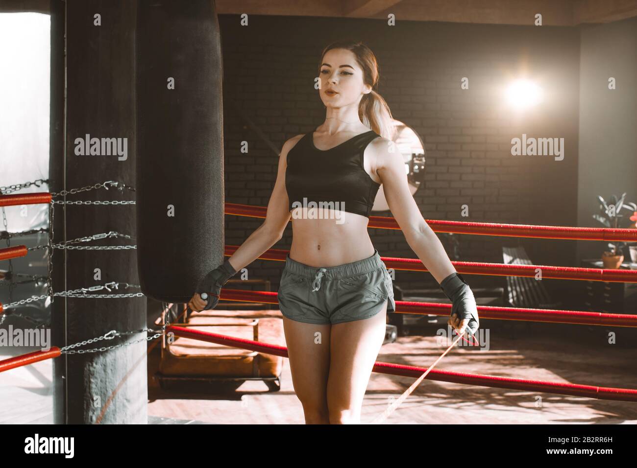 Young athletic woman exercising using skipping rope on boxing ring gym ...