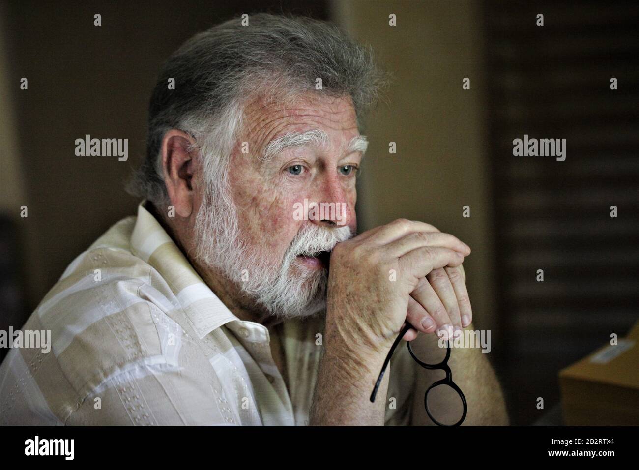 Older senior real man with round glasses and gray beard thinking with ...