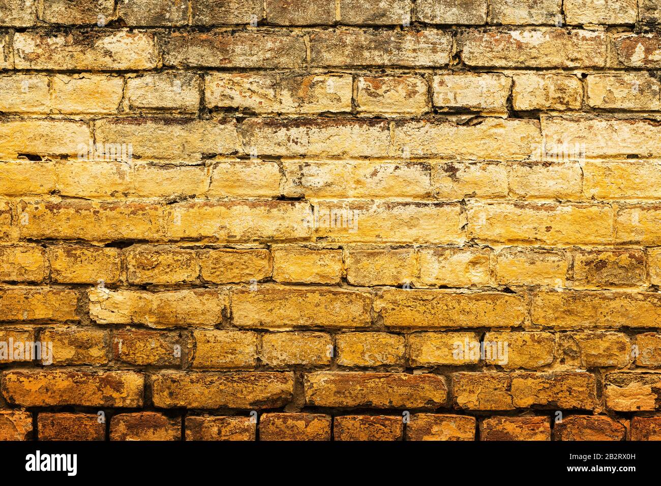 Worn yellow brick wall background, damaged old ruined house facade ...