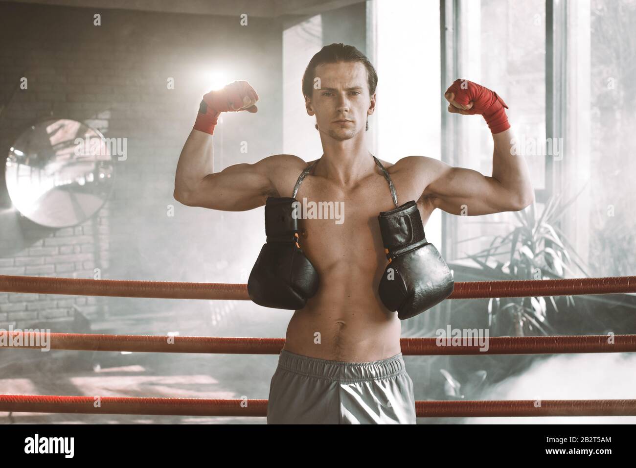 Portrait of muscular handsome boxer relaxing on boxing ring background ...