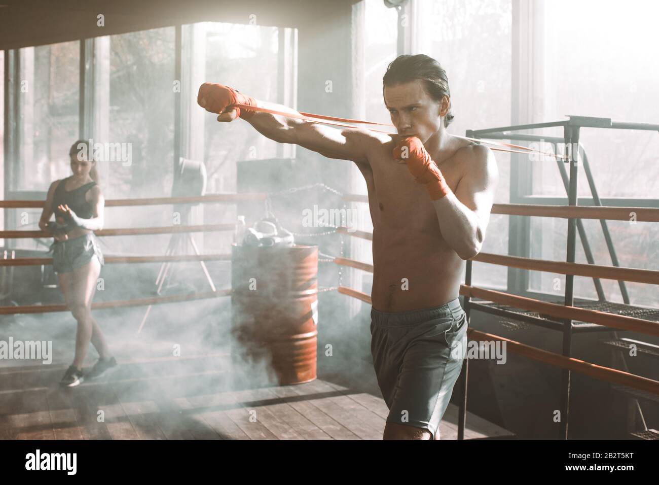Handsome man working out with resistance band in the boxing ring at the ...