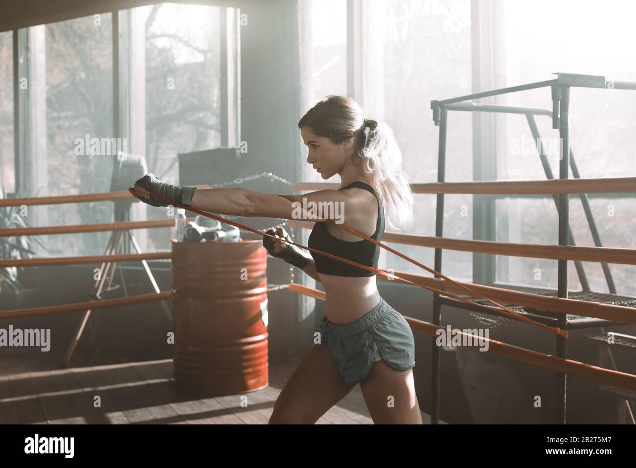 Young beautiful boxer girl pulls training punching with rubber band in ...