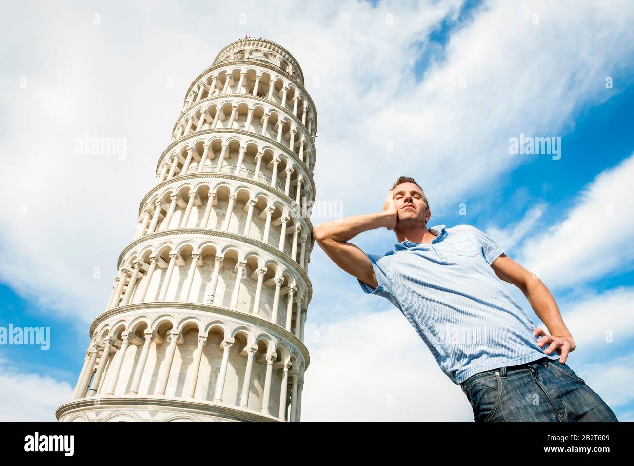Relaxed tourist leaning with his elbow against the Tower of Pisa under ...