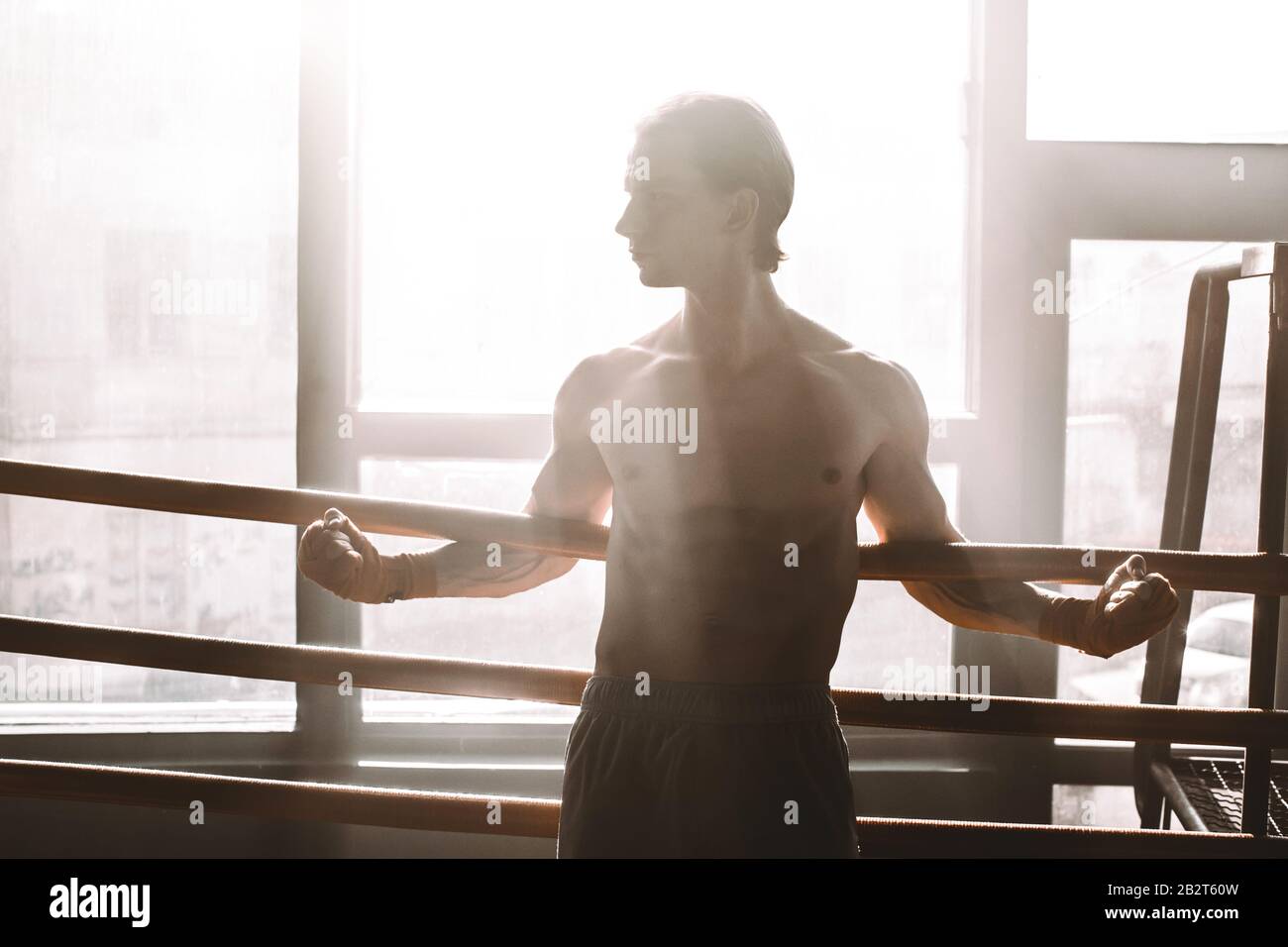 Portrait of sportive boxer wearing boxing bandages on hands while ...