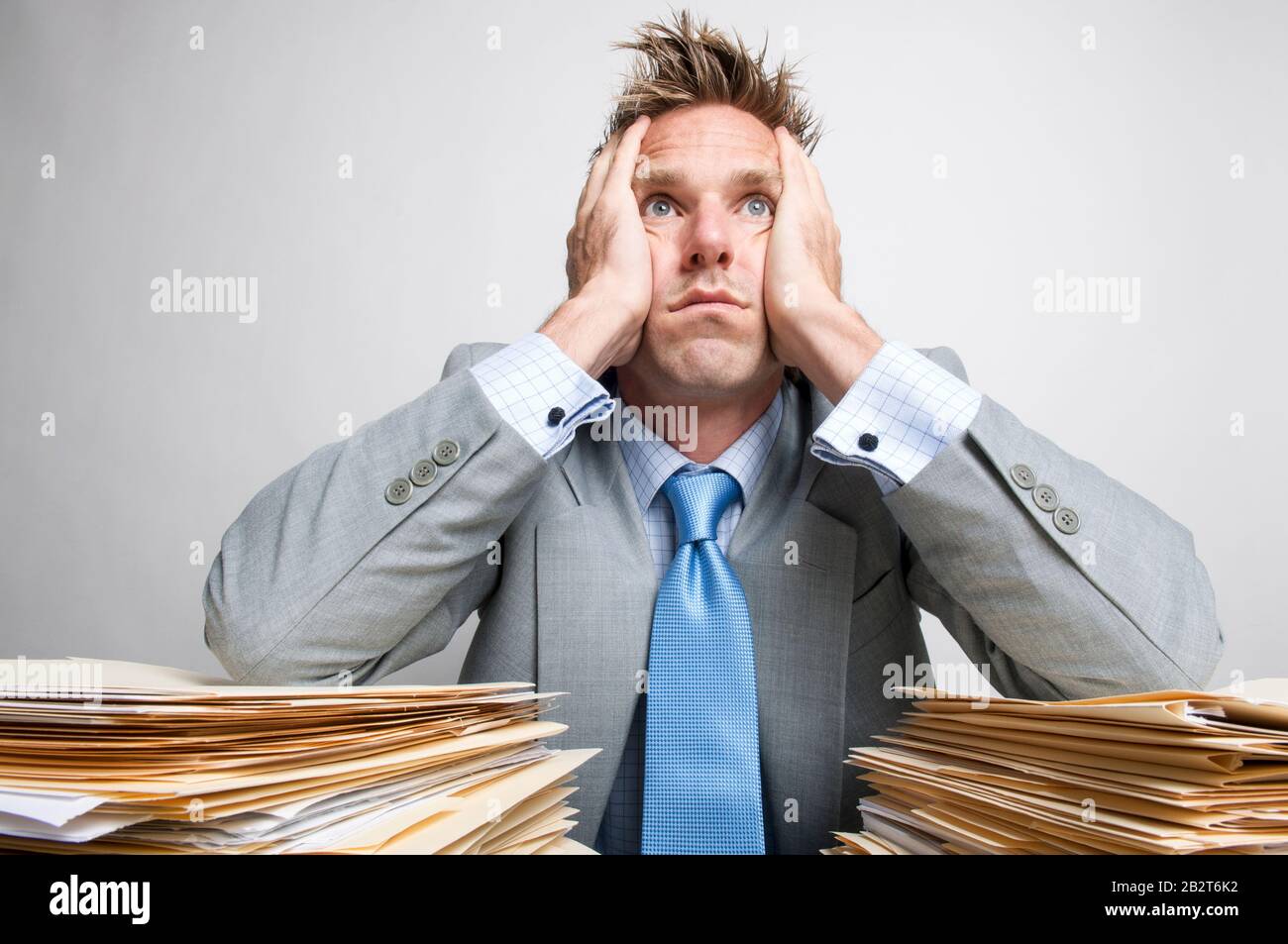 Bored businessman holding his head in his hands on the piles of ...