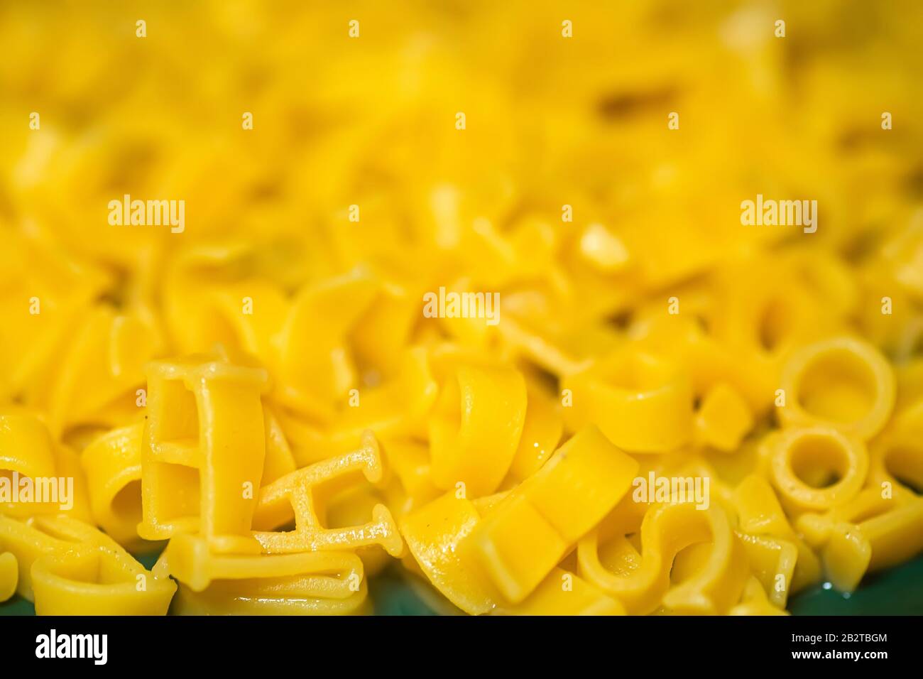 macaroni alphabet letters on a green plate. Durum wheat pasta for ...