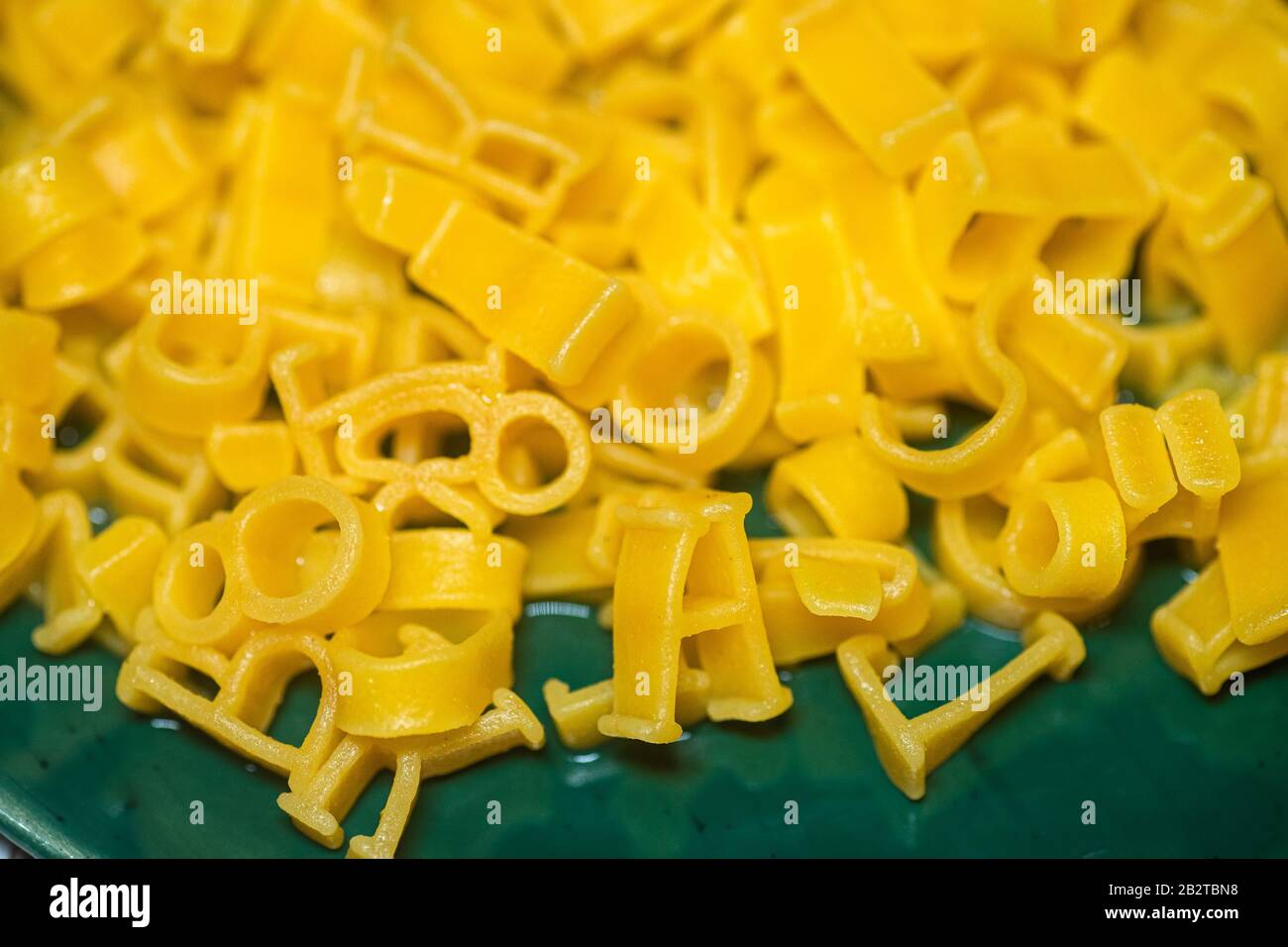 macaroni alphabet letters on a green plate. Durum wheat pasta for ...