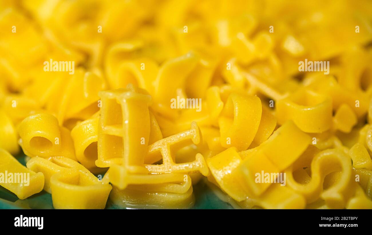 macaroni alphabet letters on a green plate. Durum wheat pasta for ...