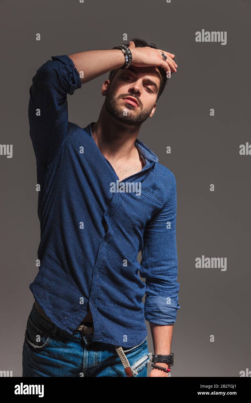 young fashion man holding hand on forehead and posing for the camera on ...