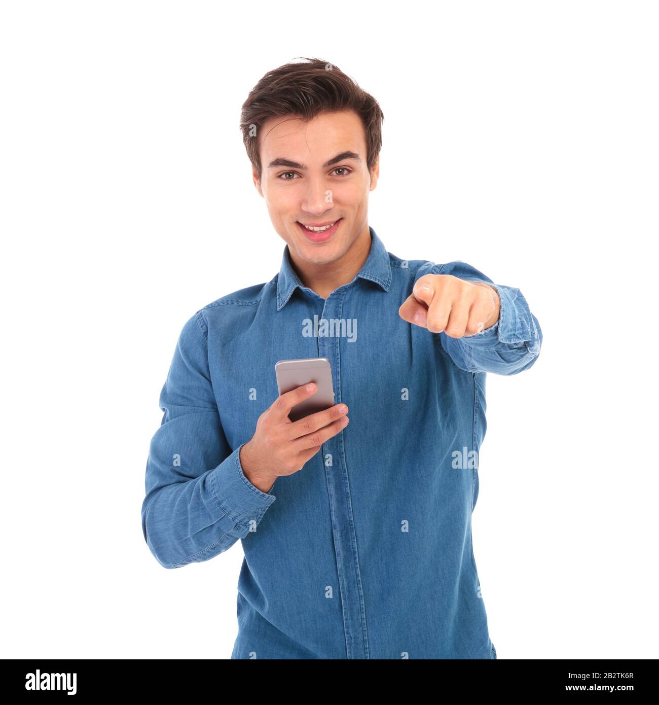 young casual man holding phone and pointing finger on white background ...
