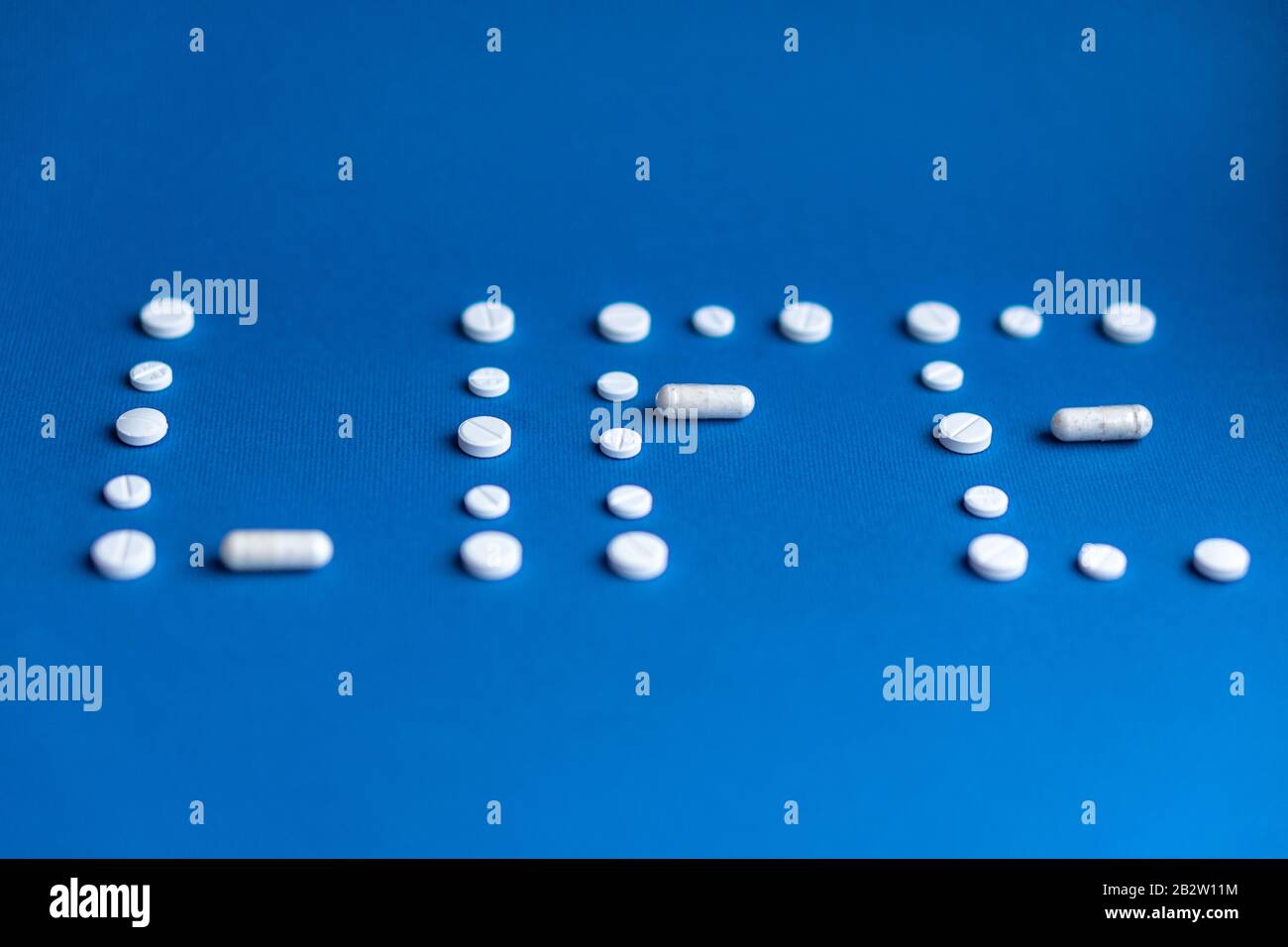 The word life made up of white pills and capsules on a classic blue ...