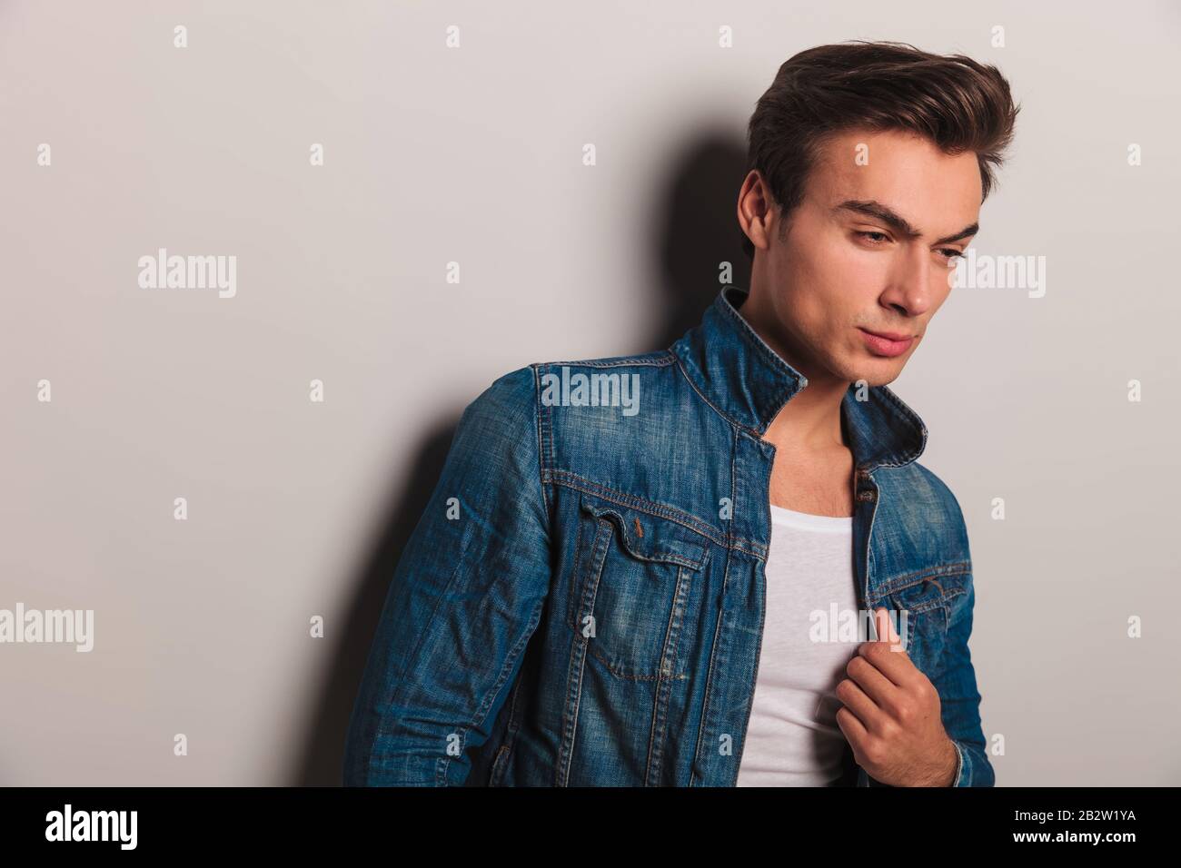 sad man in jeans jacket looks down on grey background Stock Photo - Alamy