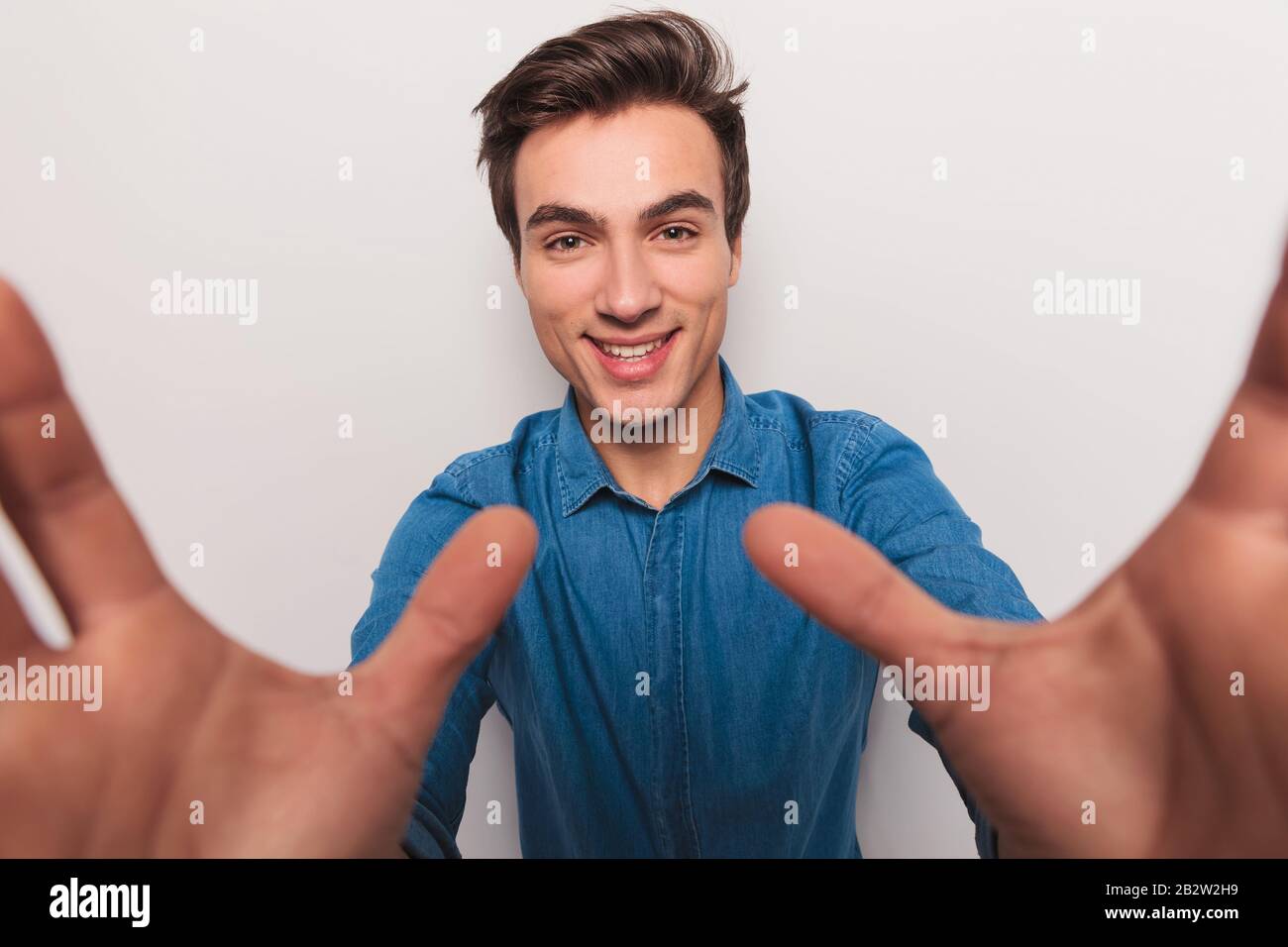 happy young man holding the camera and smiles, studio picture Stock ...