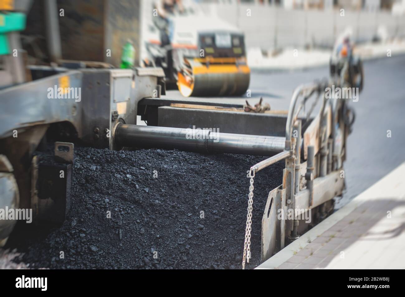 Asphalt paver machine and steam road roller during road construction ...