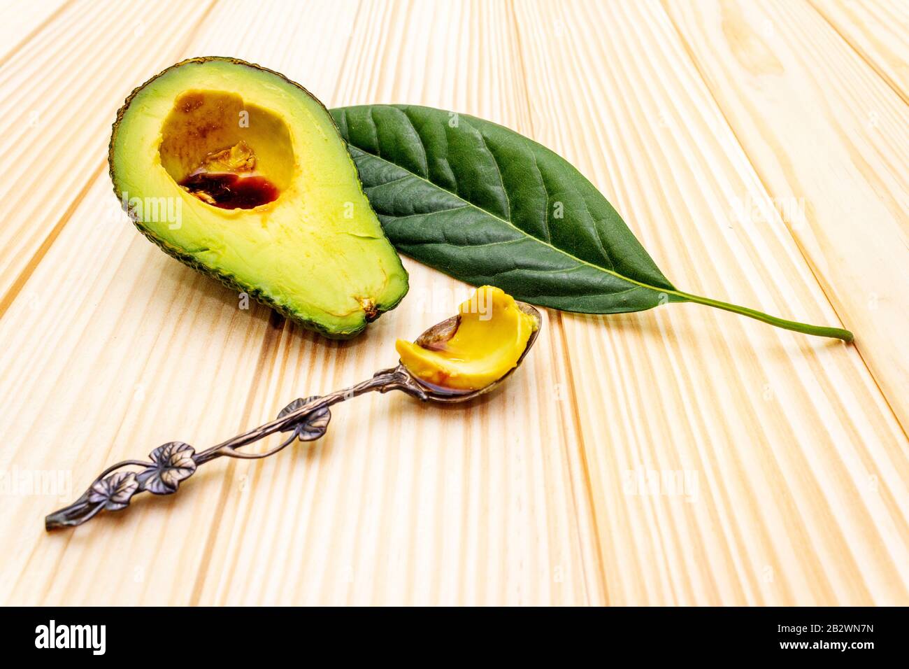 Avocado, cut in half and avocado leaf. Silver spoon with soy sauce ...