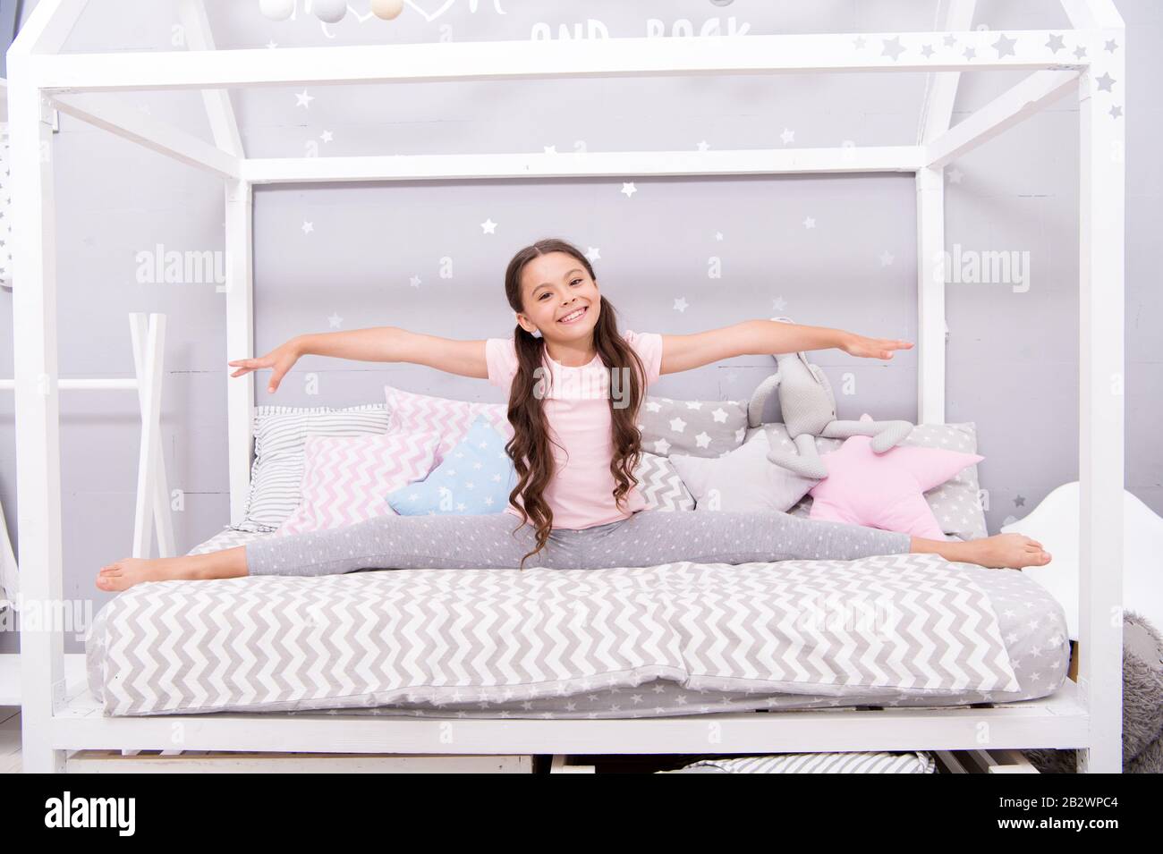 Adorable gymnast. Happy child sit in split position. Little girl do ...