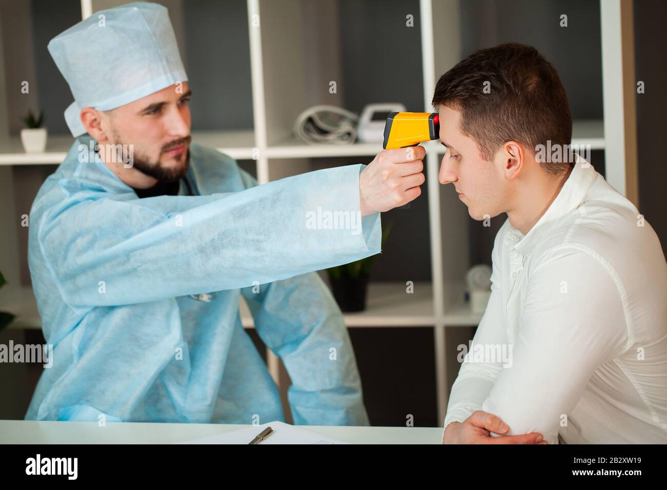 Doctor measures the patient's temperature with a laser thermometer ...