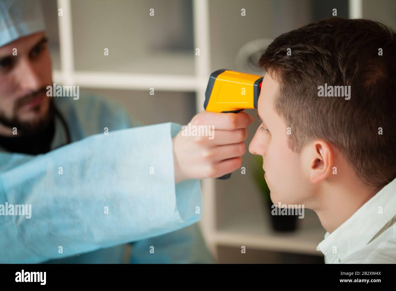 Doctor measures the patient's temperature with a laser thermometer ...