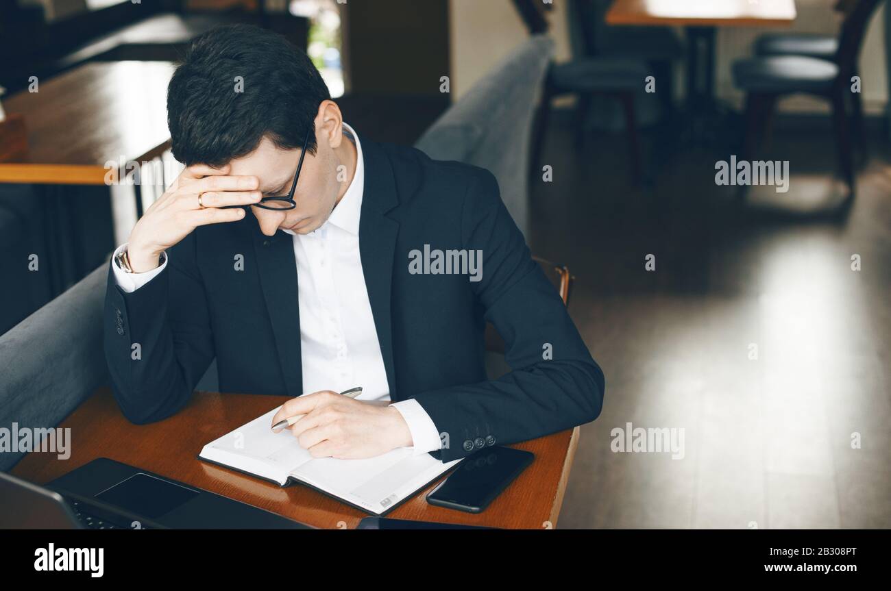 Thinking caucasian businessman is trying to write something while ...